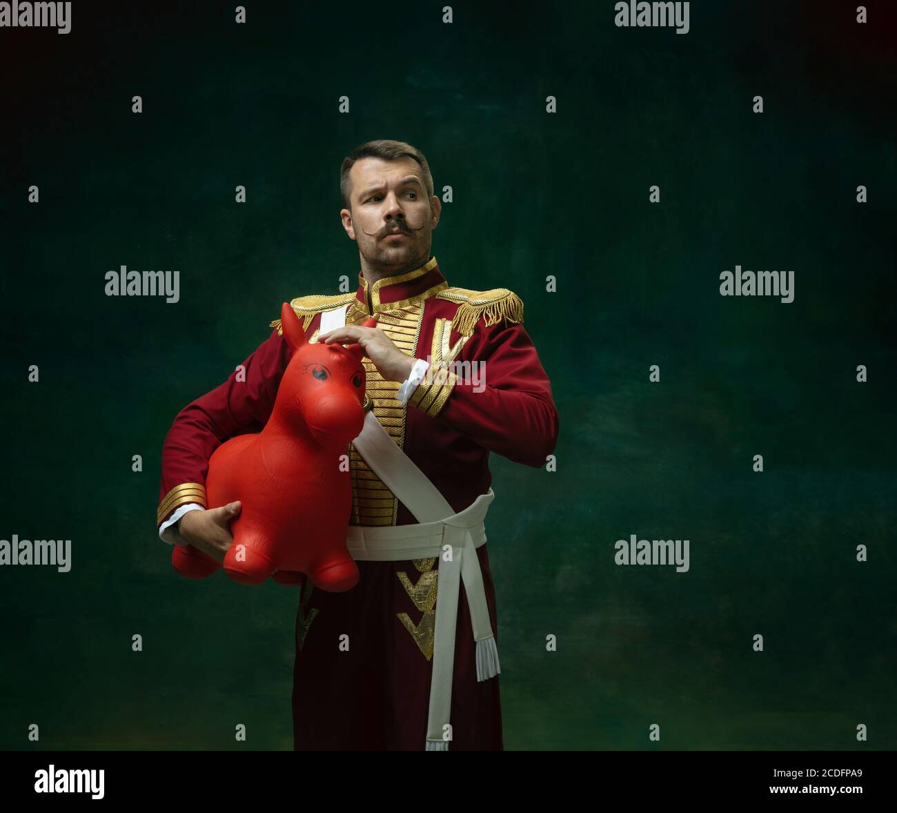 Faithful horse. Young man in suit as Nicholas II isolated on dark green ...