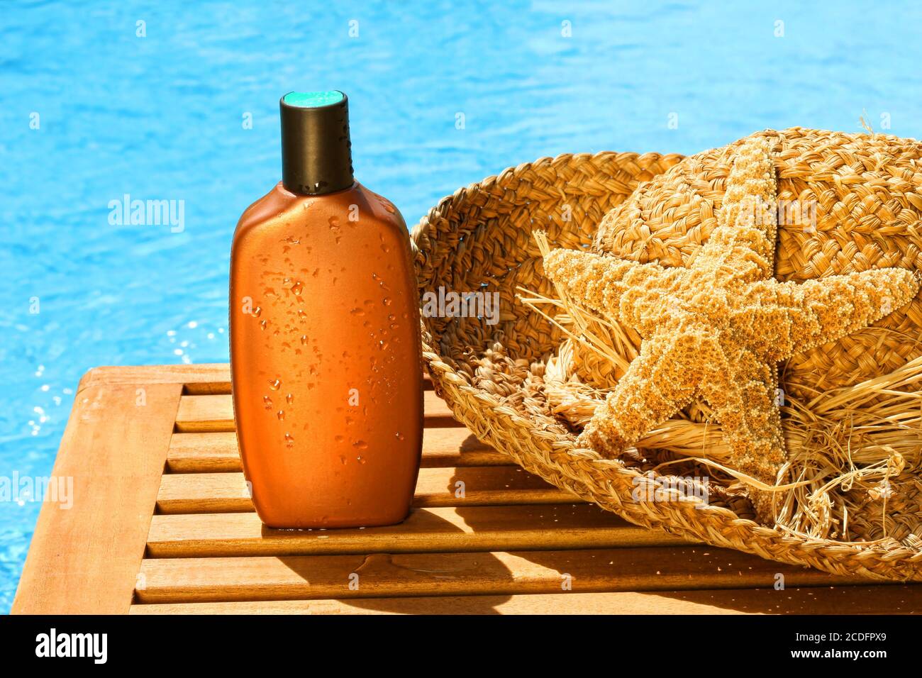 Tanning lotion with sun hat by the pool Stock Photo - Alamy
