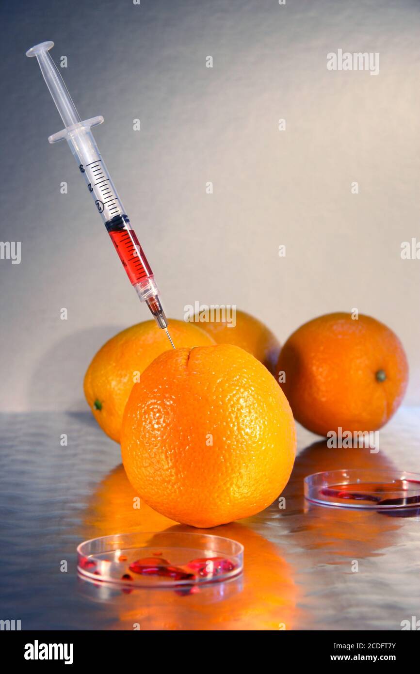 Syringe injecting liquid into an orange Stock Photo - Alamy