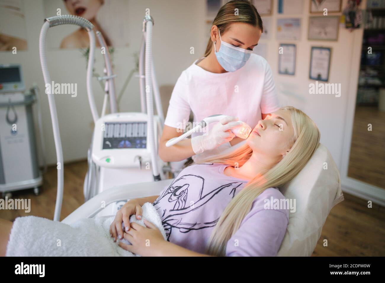 Beautiful female patient is getting a face skin treatment while lying ...