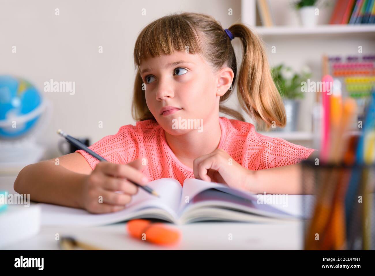 Tired girl studying school assignments in study room full of ...