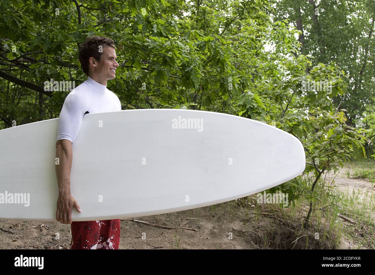 Surfer at tree line Stock Photo - Alamy
