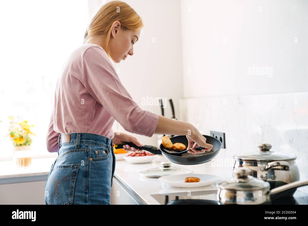 Photo of serious beautiful woman with blonde hair cooking lunch in ...