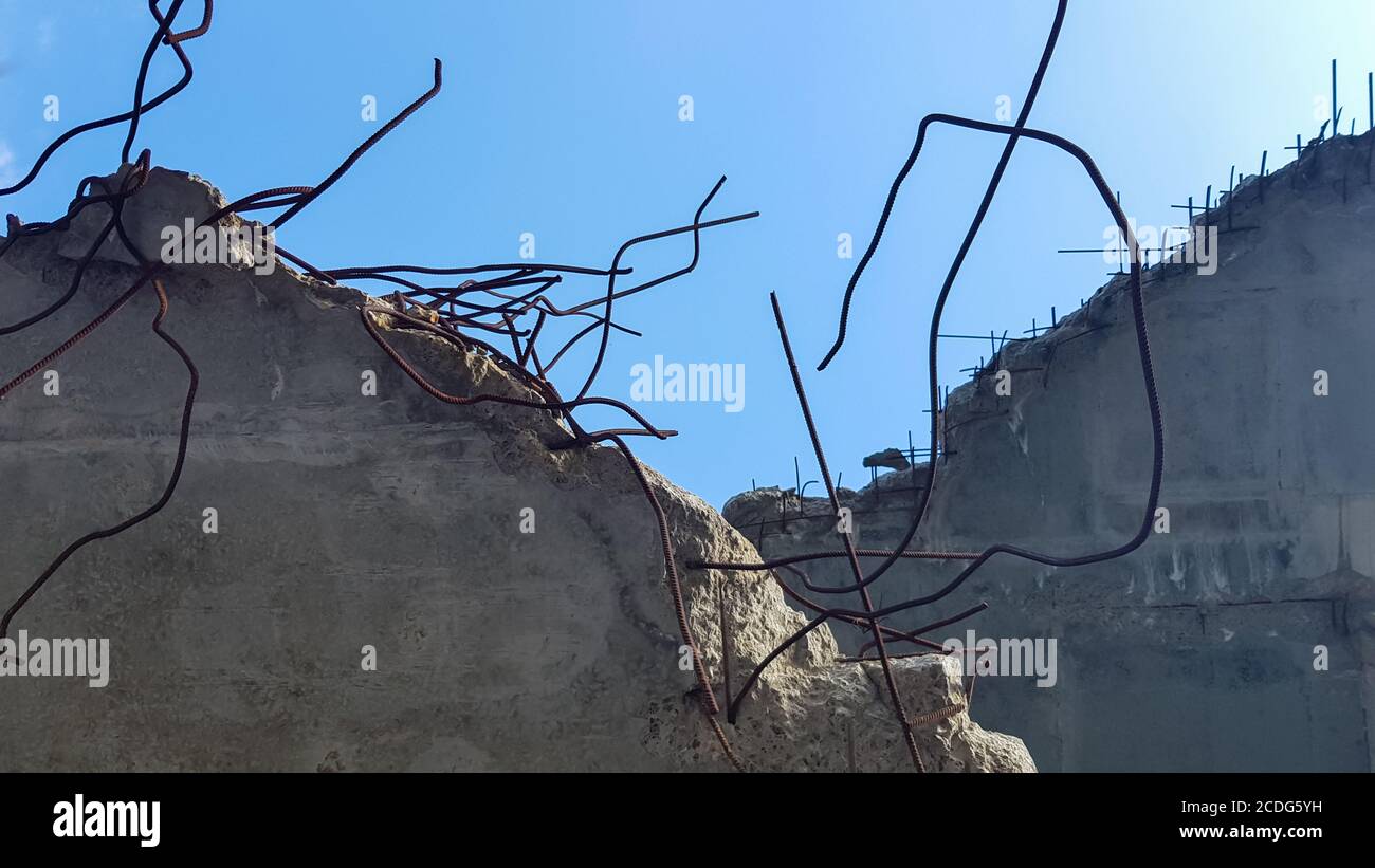 Destruction of a concrete structure with reinforcement against a blue ...