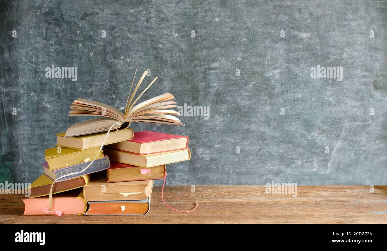 Stack of books in front of a blackboard. Back to school, reading ...