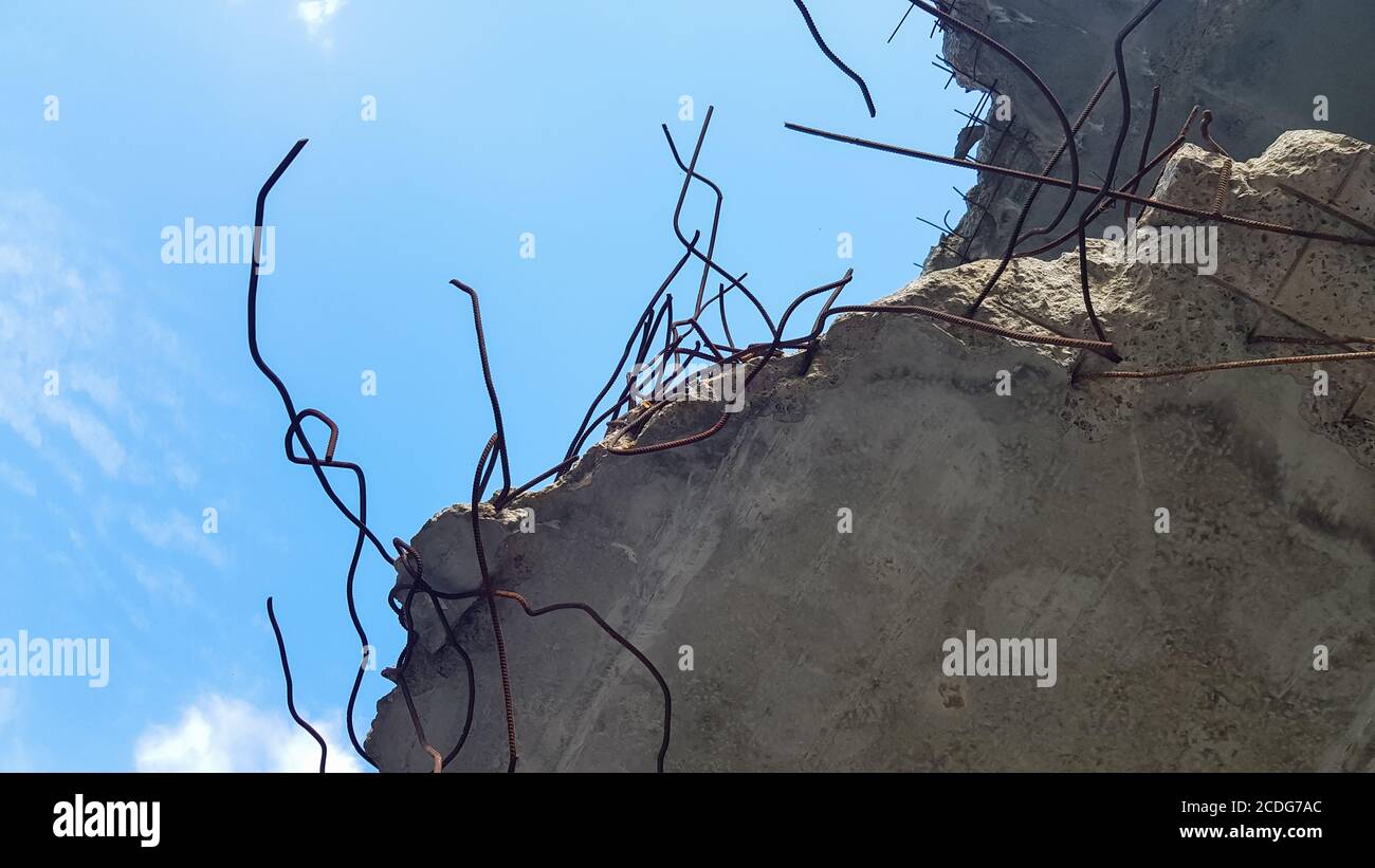 Destruction of a concrete structure with reinforcement against a blue ...