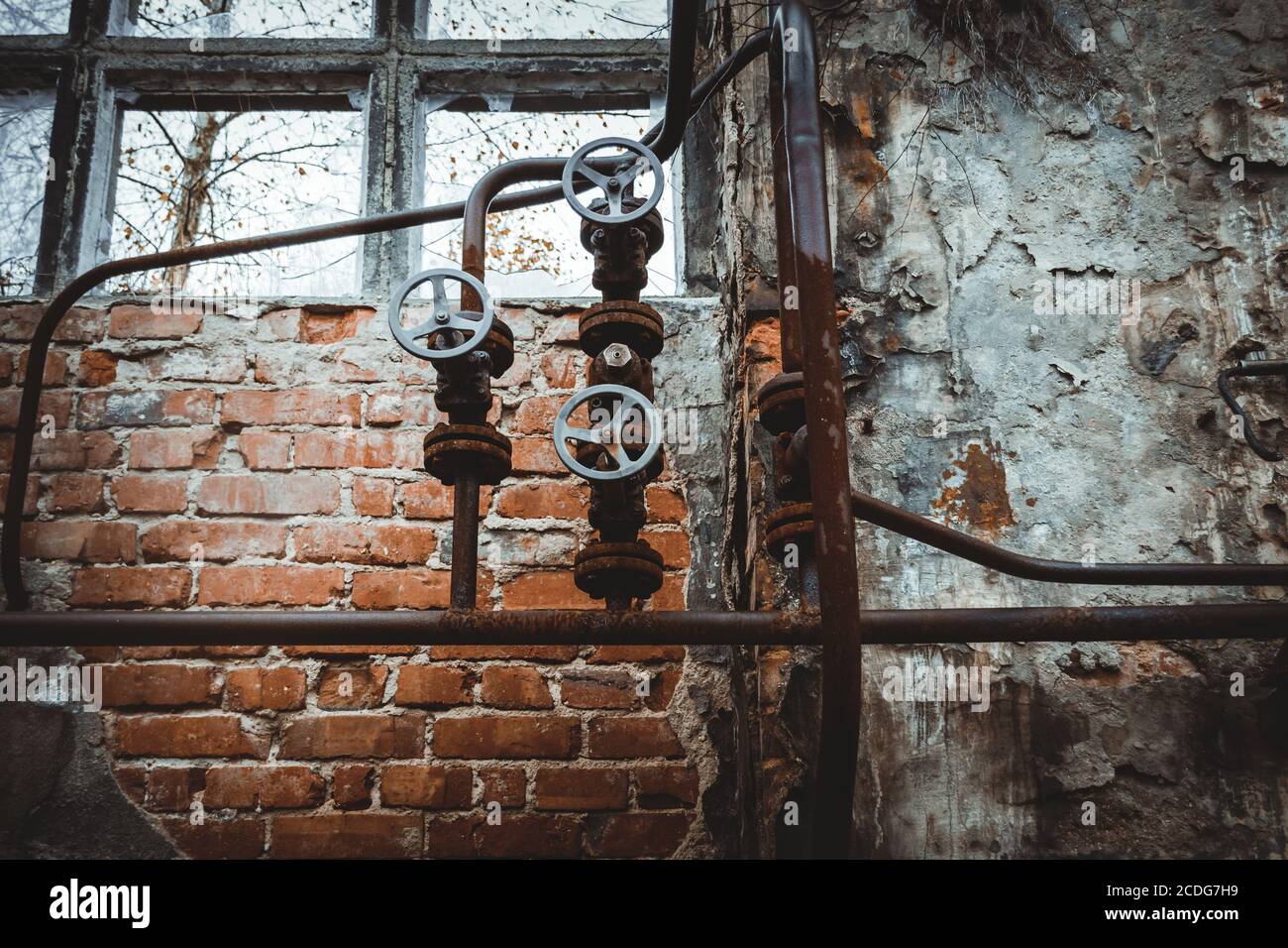 Closeup shot of old water pipes over old brick wall and grey windows ...