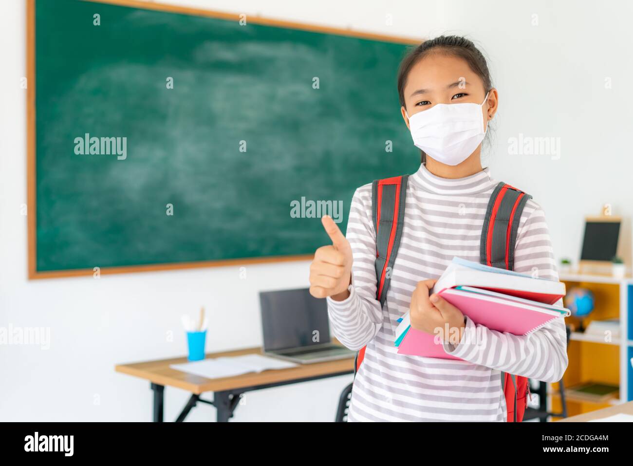 Asian primary student girl thumb up and wearing masks to prevent the ...