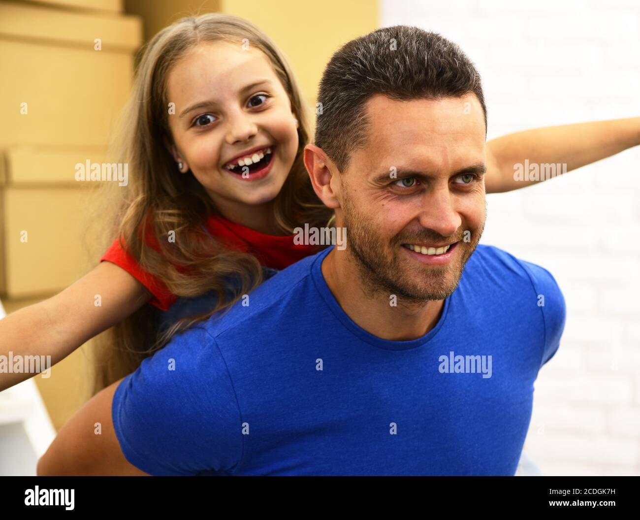Man and girl pretend to fly on white brick wall background. Dad and ...