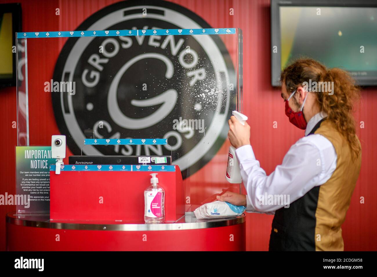 Staff clean clear plastic screens in the reception with disinfectant at ...