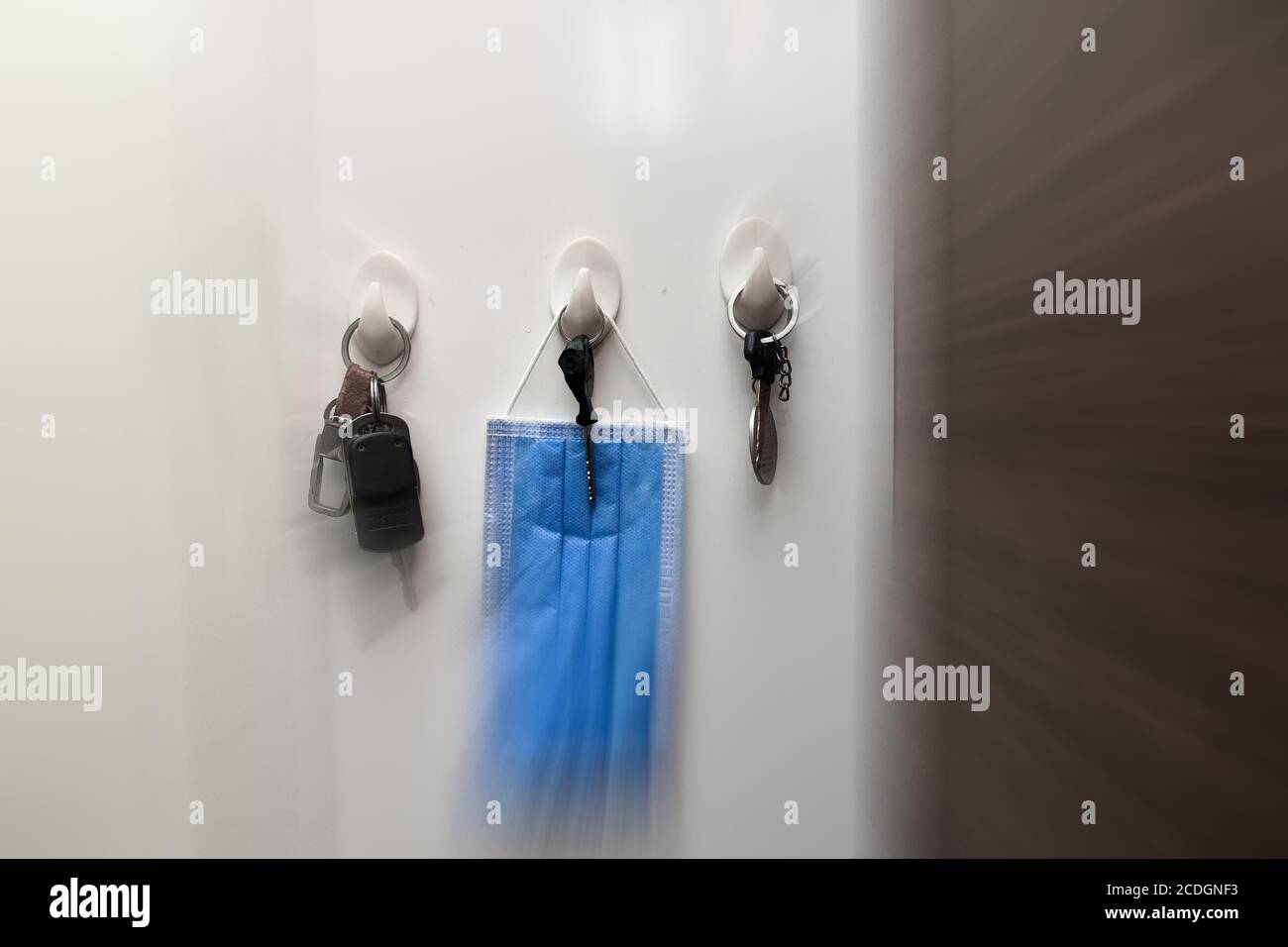 keys and a medical face mask hang on a key hanger rack with motion blur ...