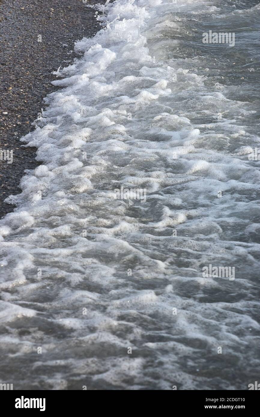 Sea foam formed from waves rolling on coast Stock Photo - Alamy