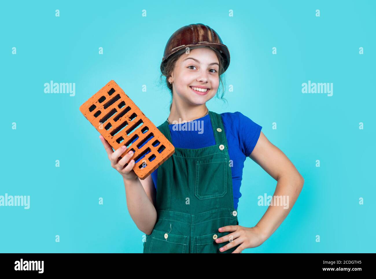 International workers day. girl in helmet plays builder with brick ...