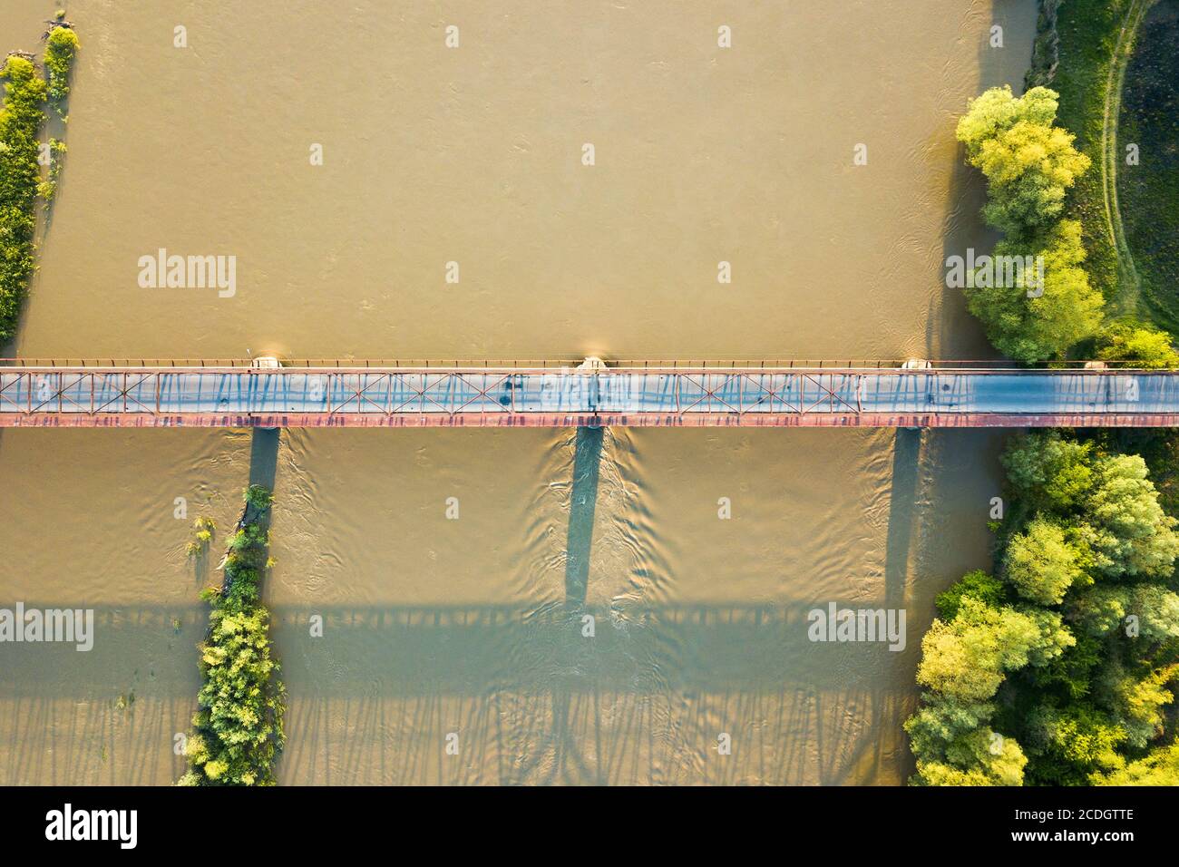 Aerial view of a narrow road bridge stretching over muddy wide river in ...