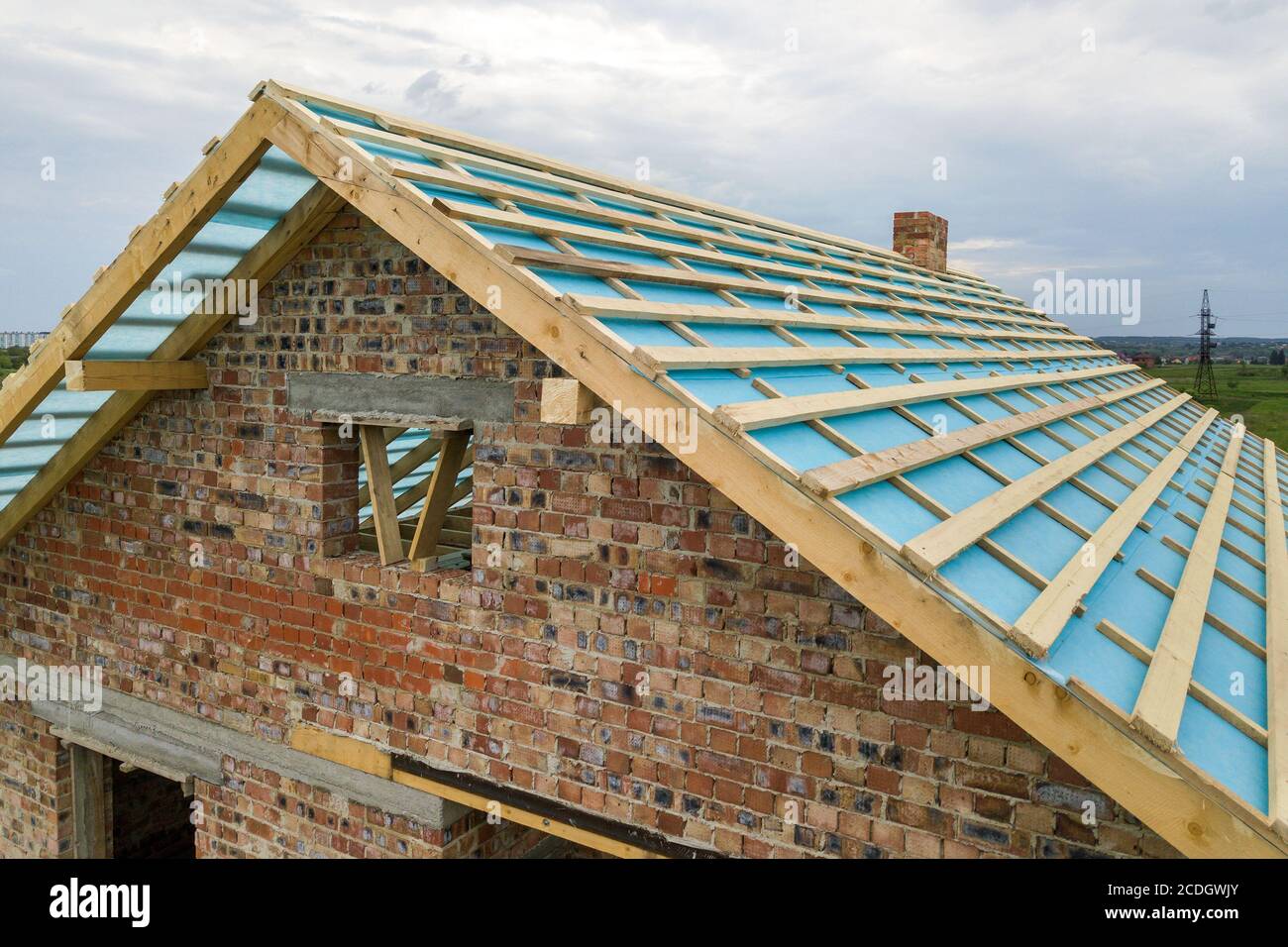 Aerial view of a brick house with wooden roof frame under construction ...