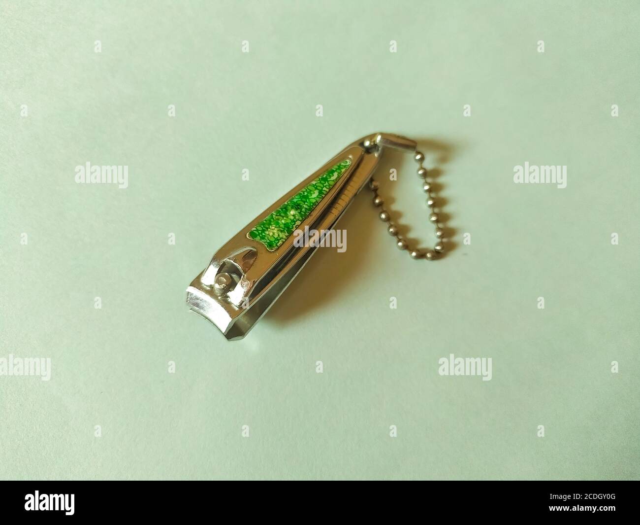 Steel nail clipper isolated on mint color background. Green design on ...