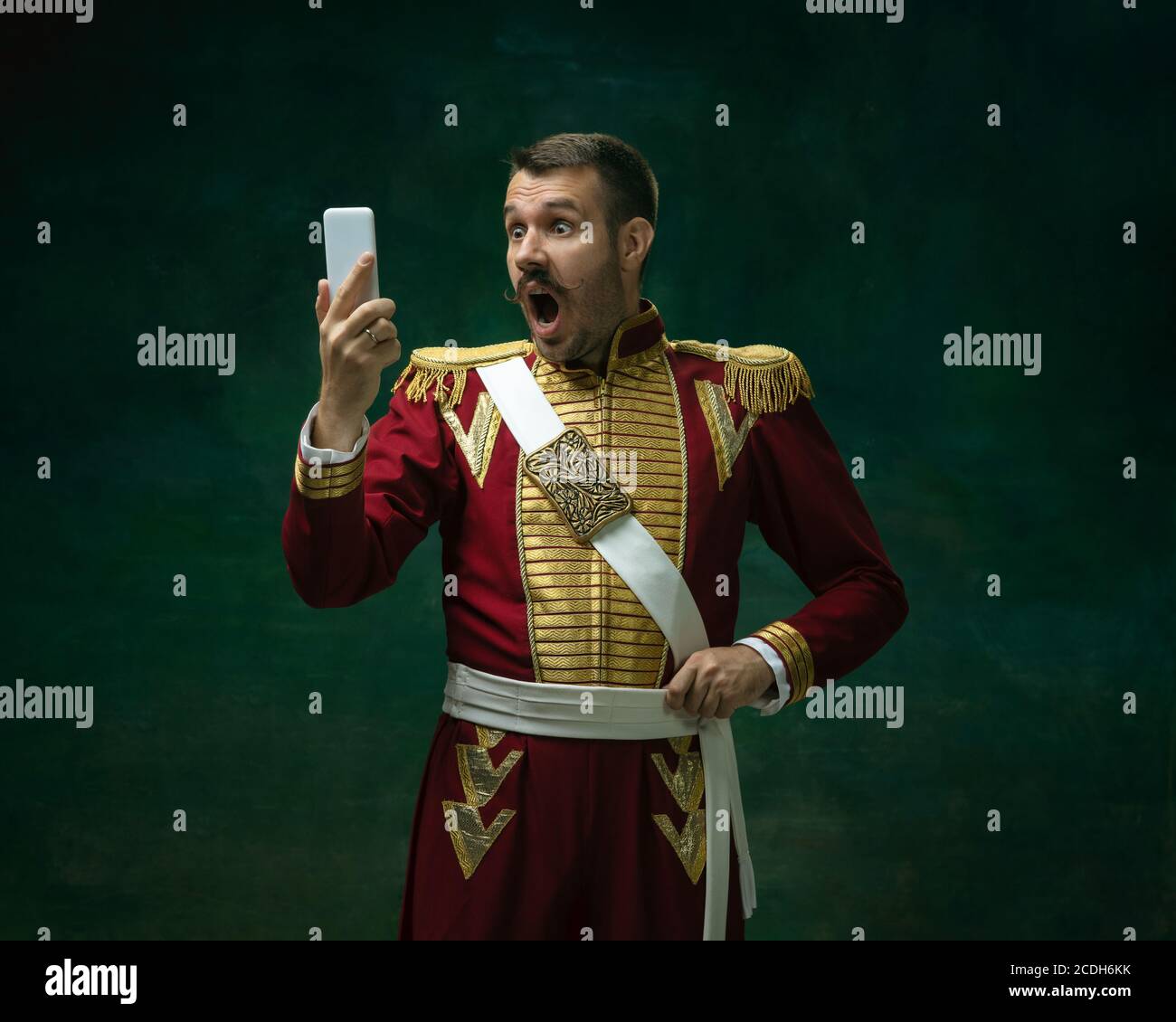 Shocked selfie. Young man in suit as Nicholas II isolated on dark green ...
