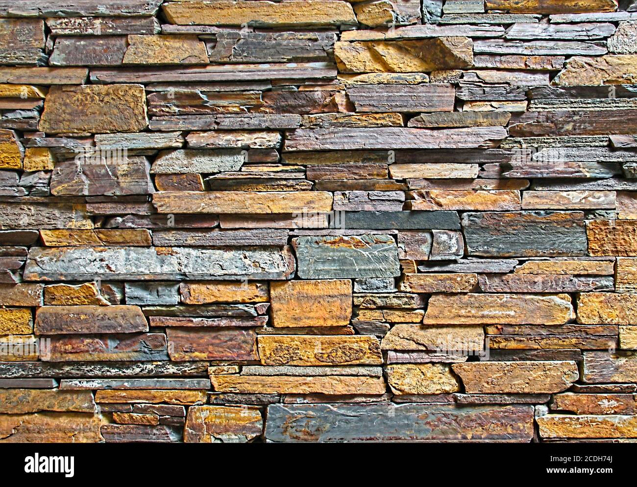 Background wall of narrow yellow and gray rectangular stones and bricks ...