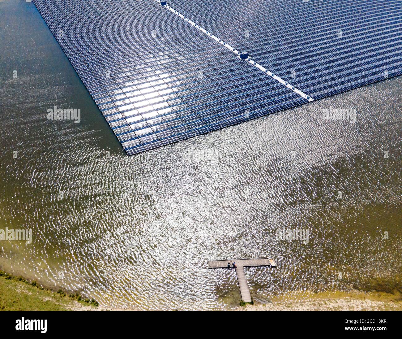 People on jetty enjoying beautiful landscape with floating solar panels ...