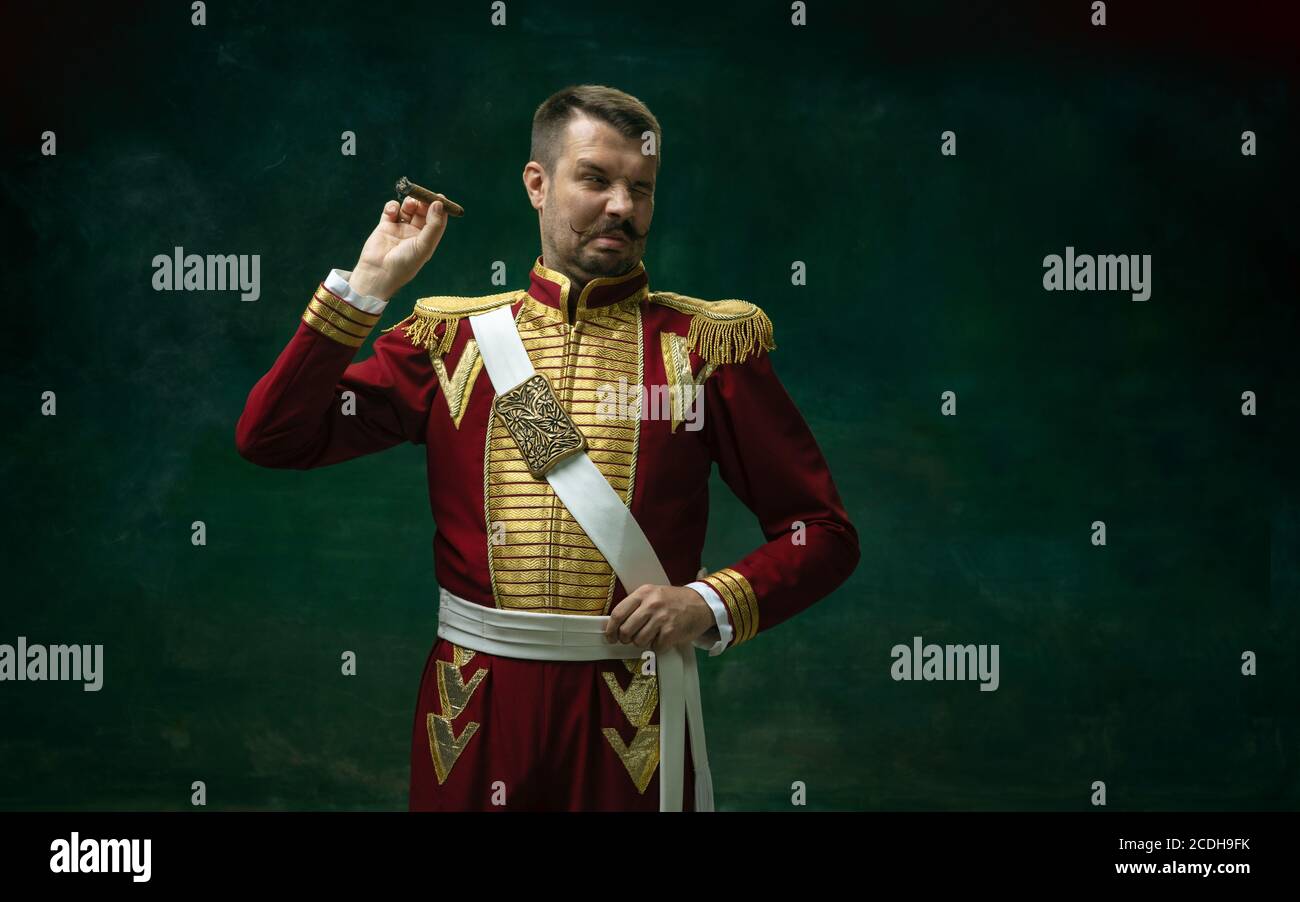 Disguasted smoking cigarette. Young man in suit as Nicholas II on dark ...