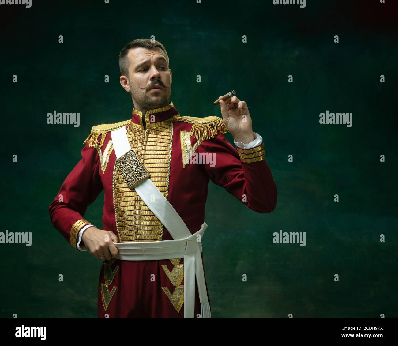 Smoking cigarette. Young man in suit as Nicholas II isolated on dark ...