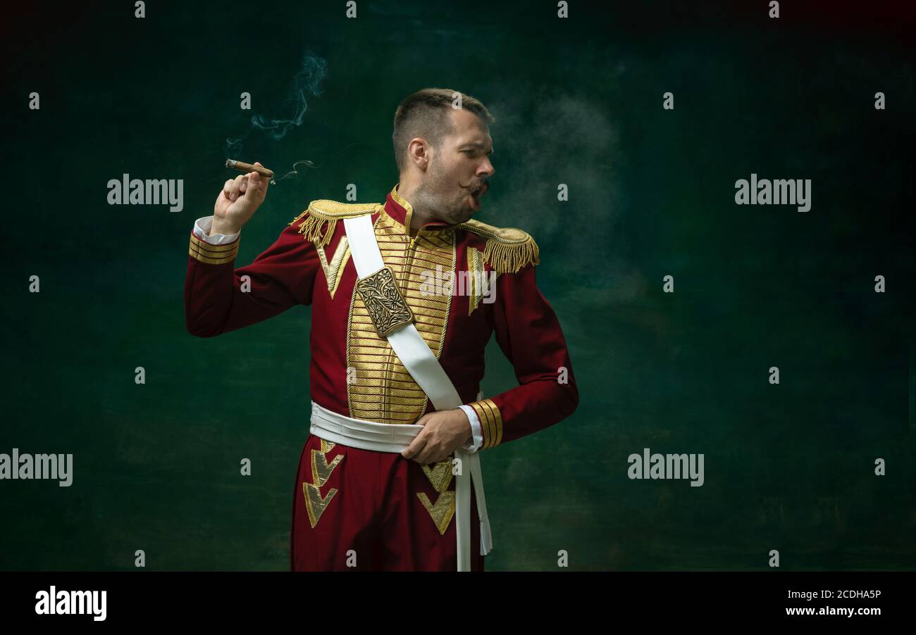 Disguasted smoking cigarette. Young man in suit as Nicholas II on dark ...