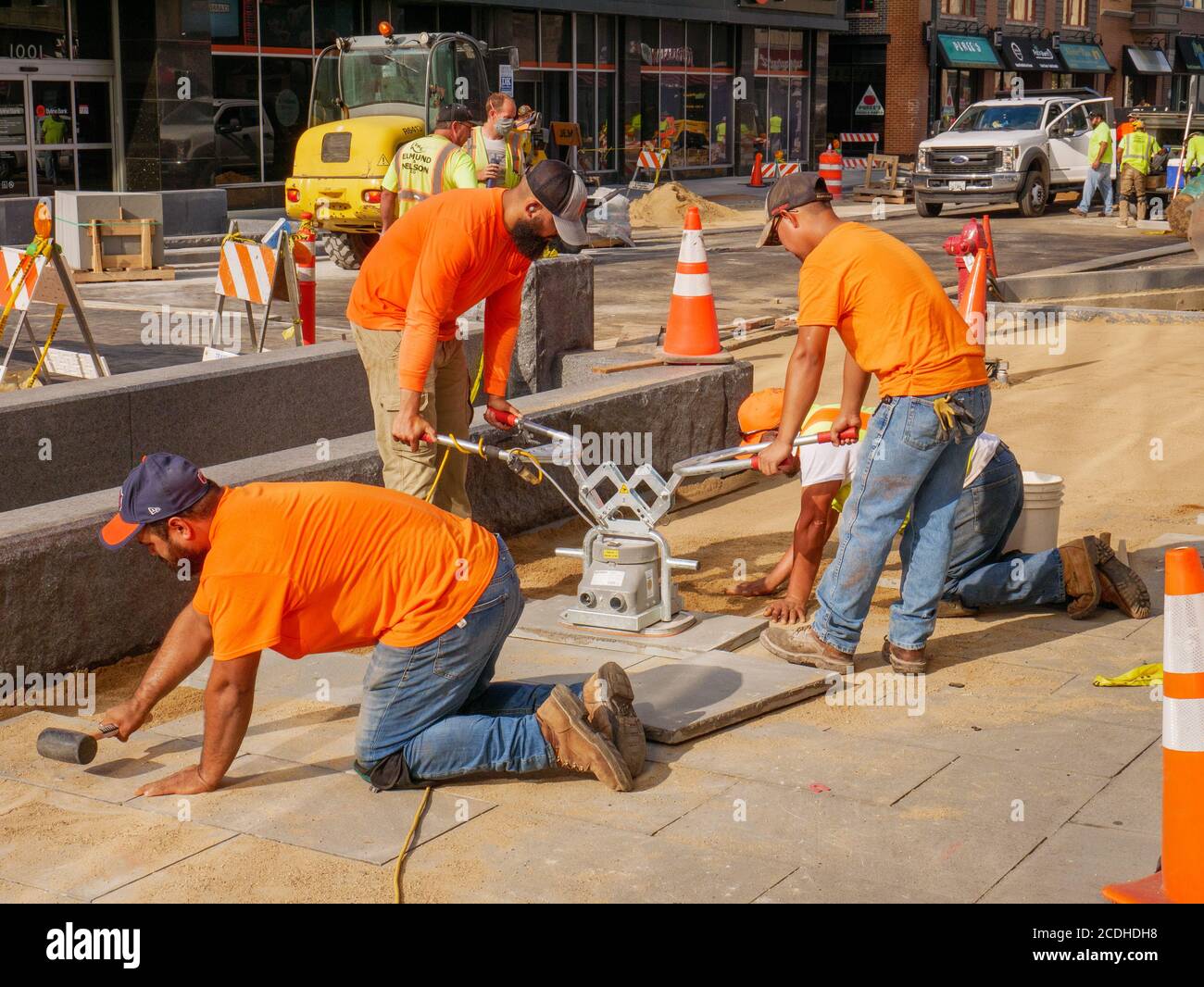 Construction workers using electric suction lifter to place pavement ...