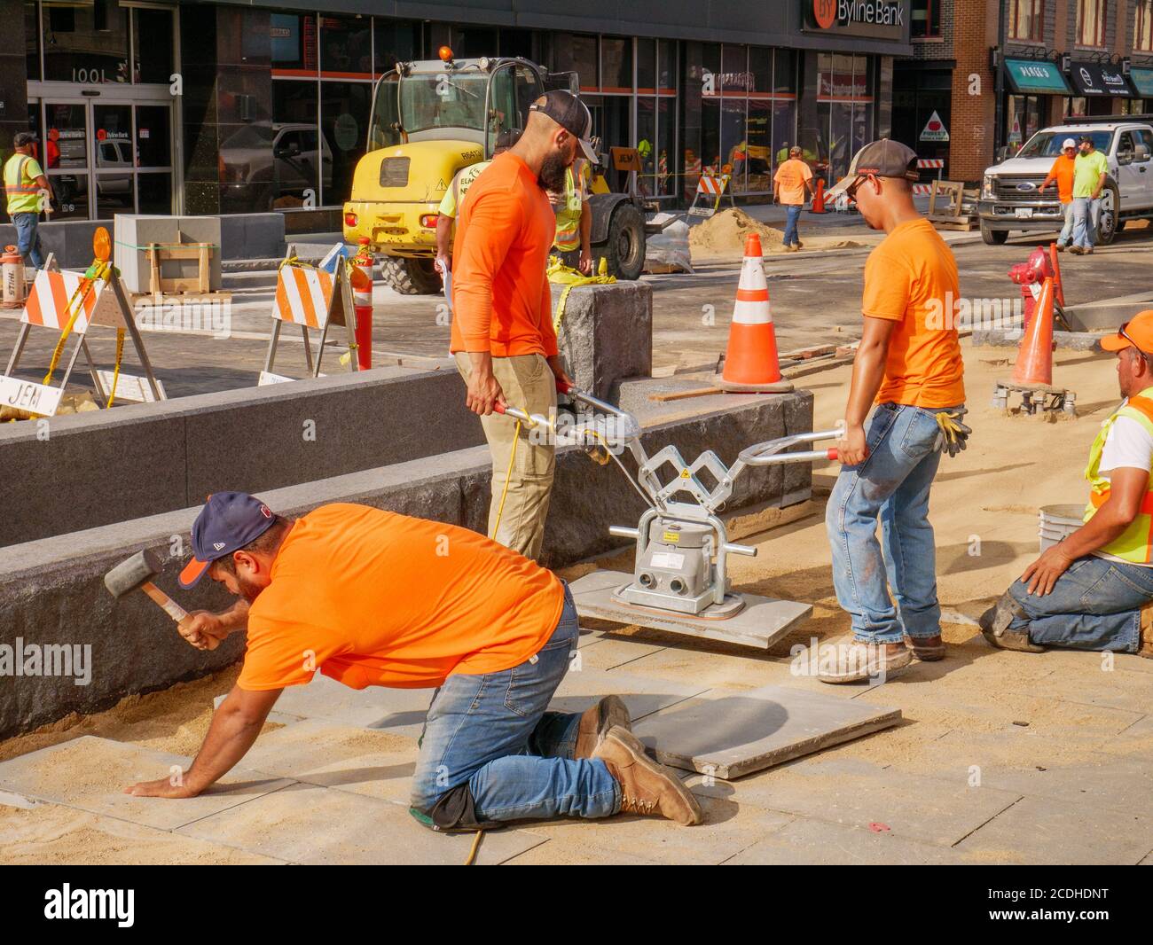 Construction workers using electric suction lifter to place pavement ...
