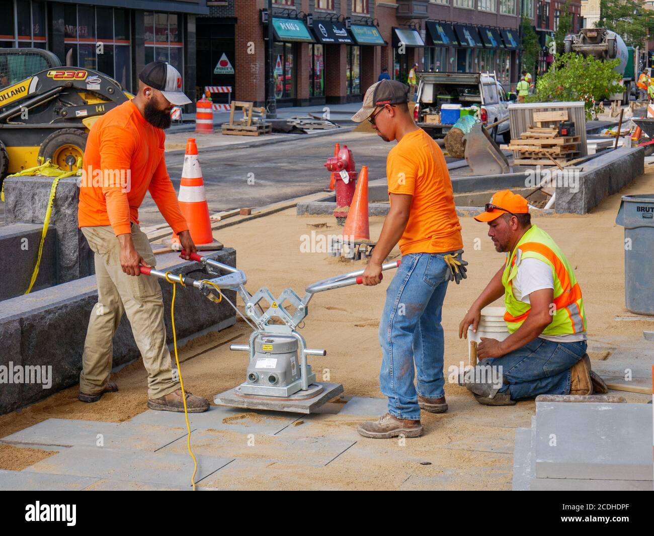 Construction workers using electric suction lifter to place pavement ...