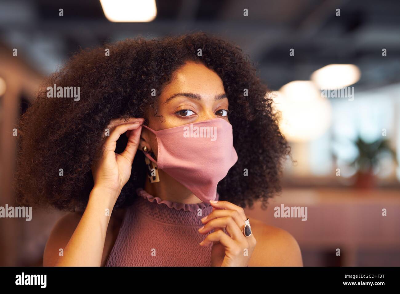 African woman putting on face mask before leaving office Stock Photo ...