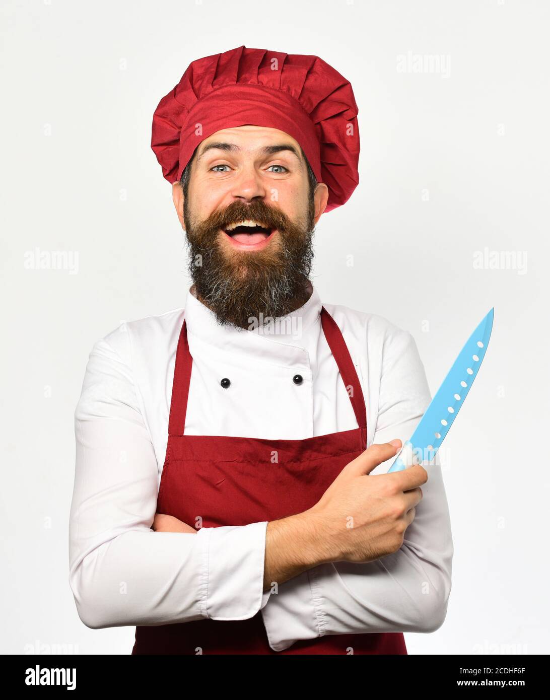 Chef holds sharp blue knife. Cook with happy face in burgundy apron and ...