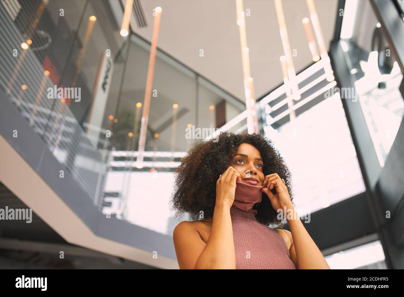 African woman putting on face mask before leaving office Stock Photo ...