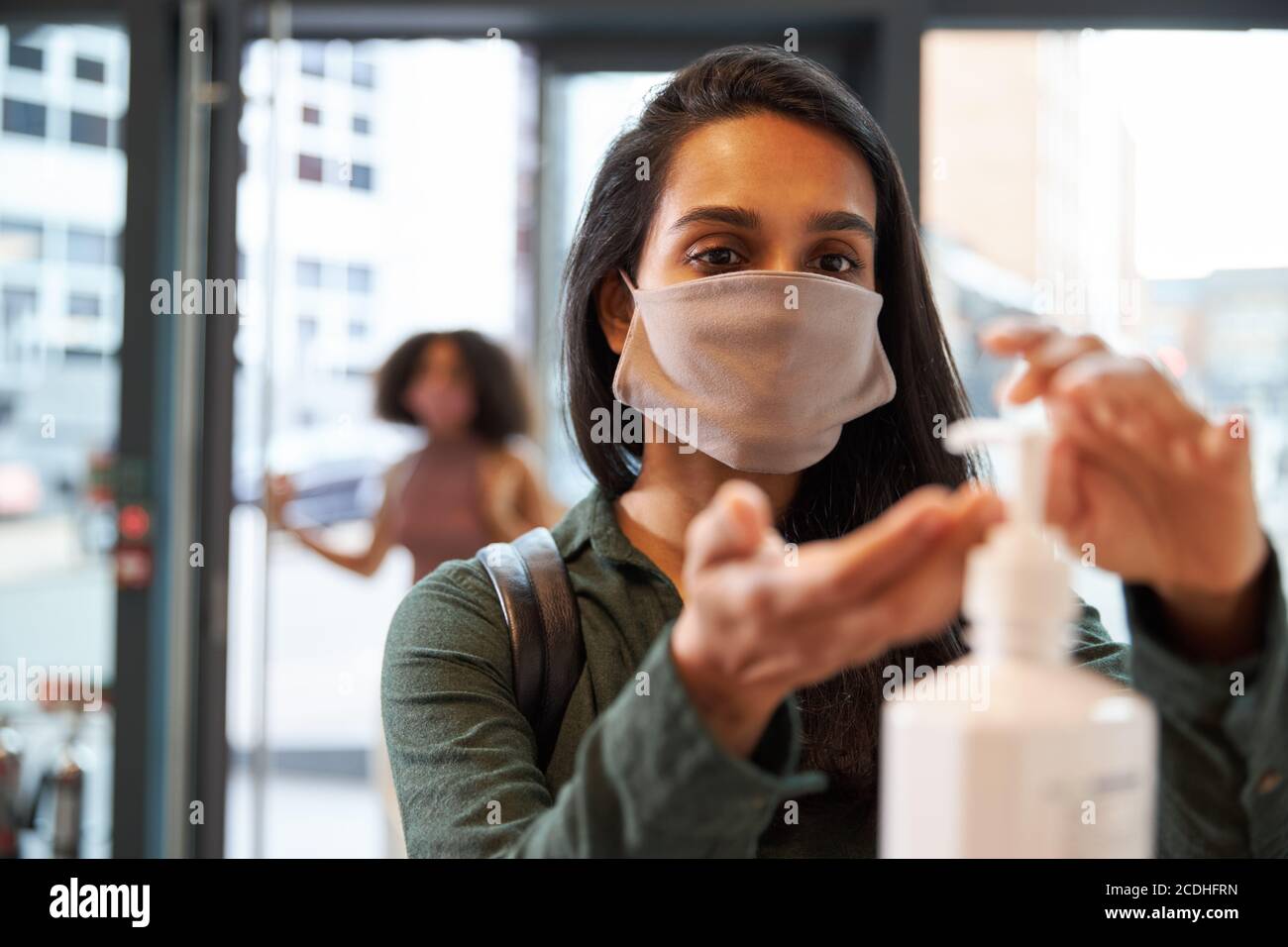 Businesswoman using hand gel before entering office at reception Stock ...