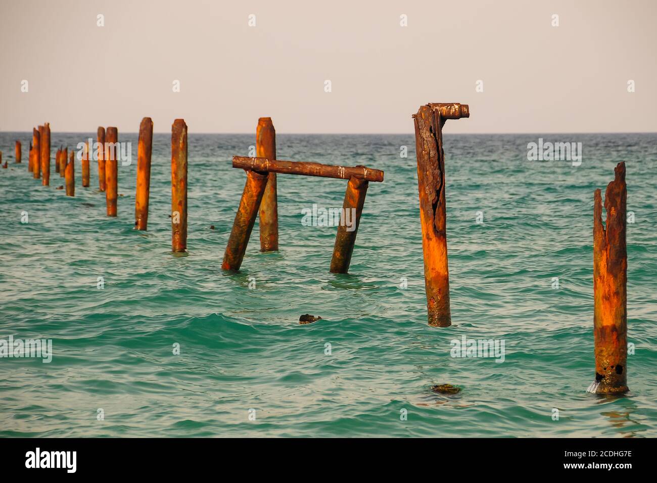 Seascape with blue calm water and rows of Rusty pipes with green algae ...