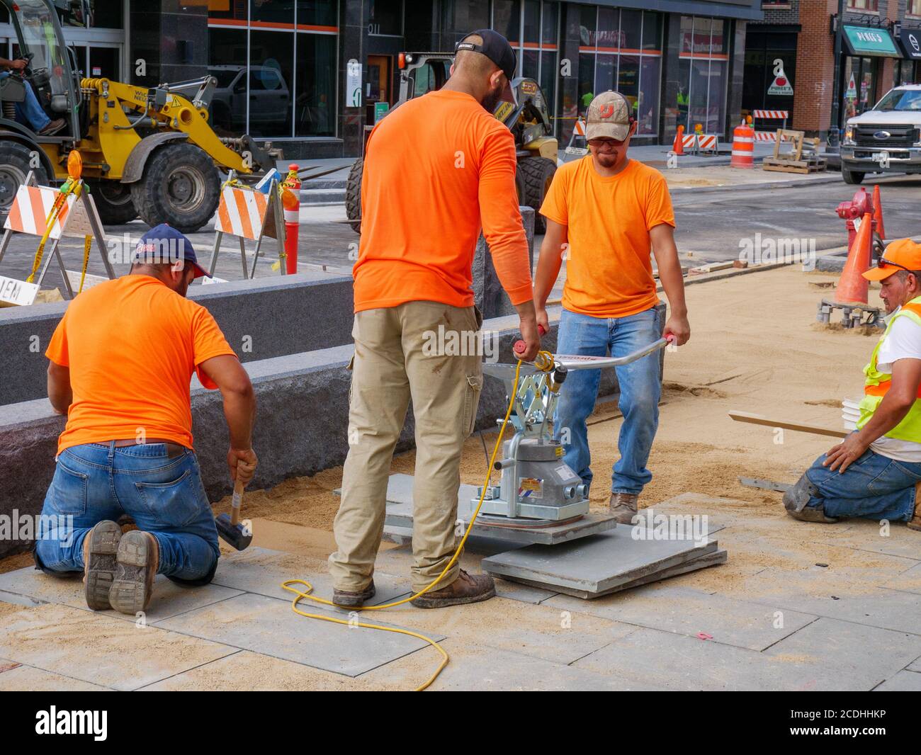 Construction workers using electric suction lifter to place pavement ...
