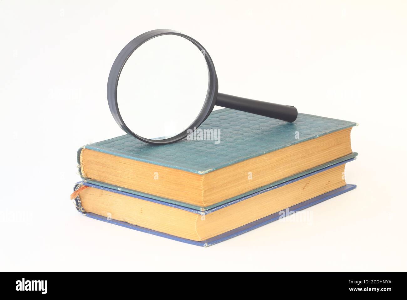 Still-life from a magnifier and a pile of old books on a white ...