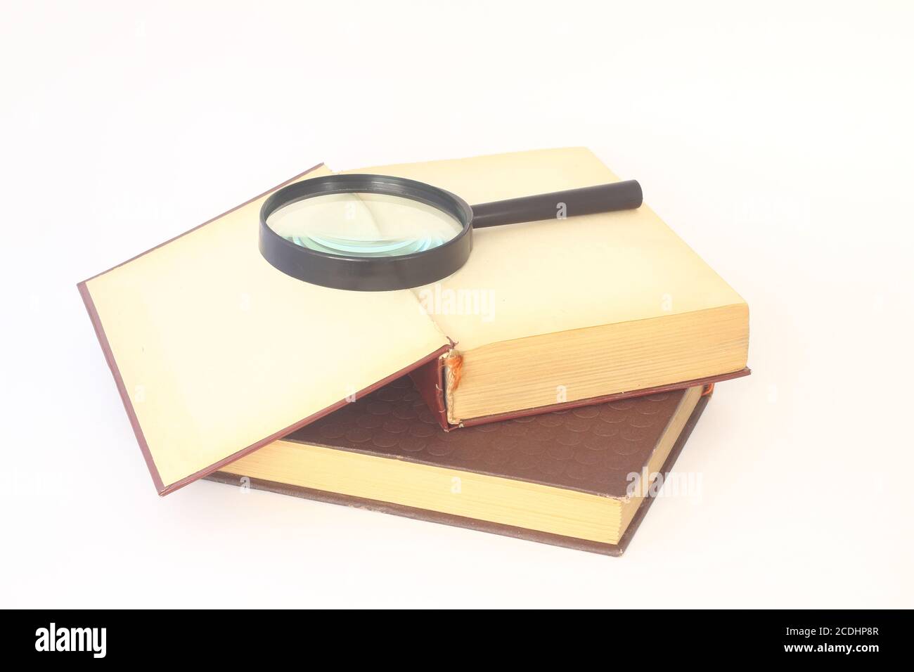 Still-life from a magnifier and a pile of old books on a white ...