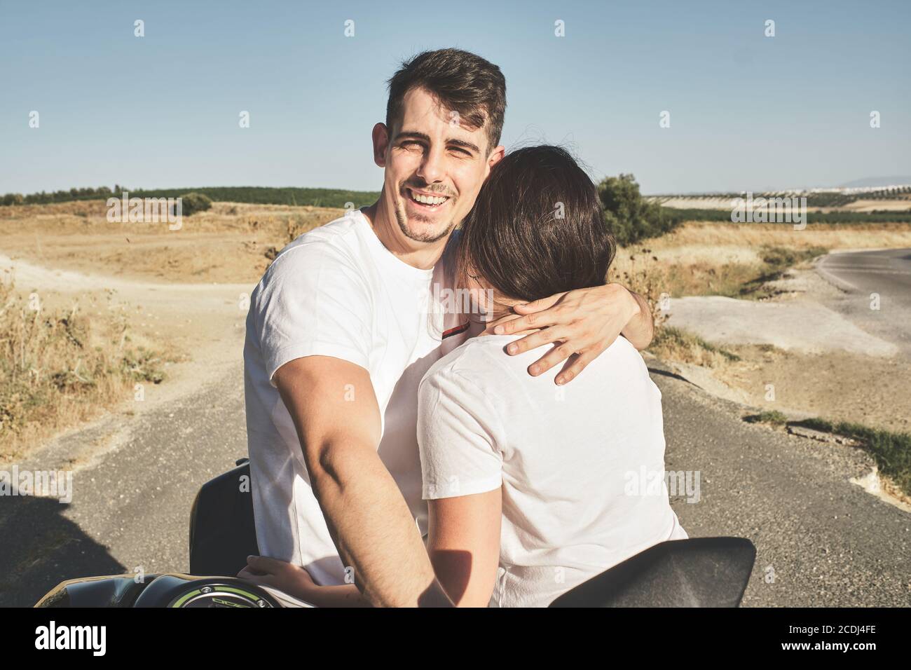 girl hugs her boyfriend, while boy looks and smiles on camera Stock ...