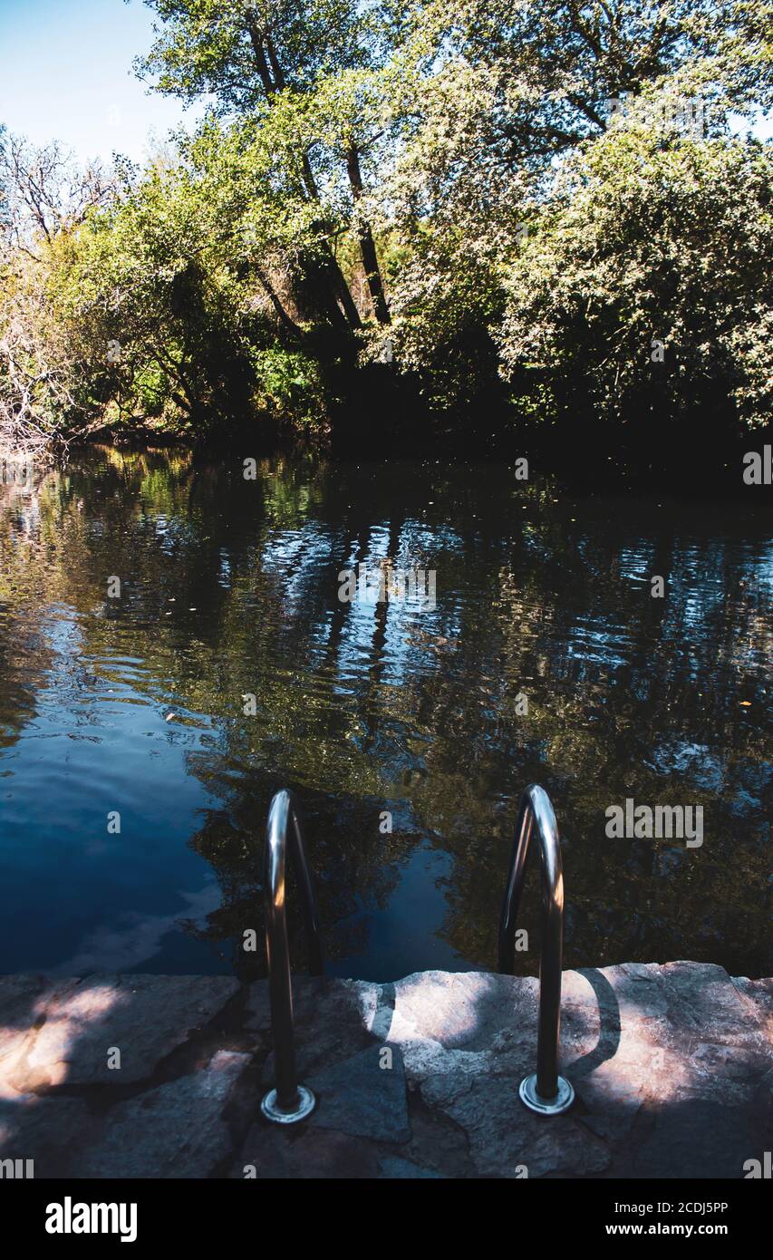 pool ladder in the middle of a river surrounded by trees reflected ...
