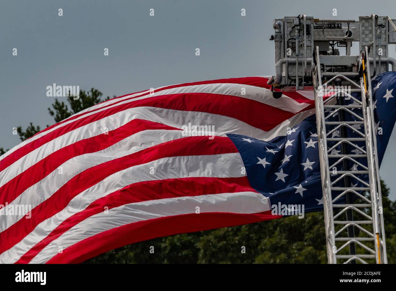 A enormous American flag is blown by the breeze as it suspended below ...