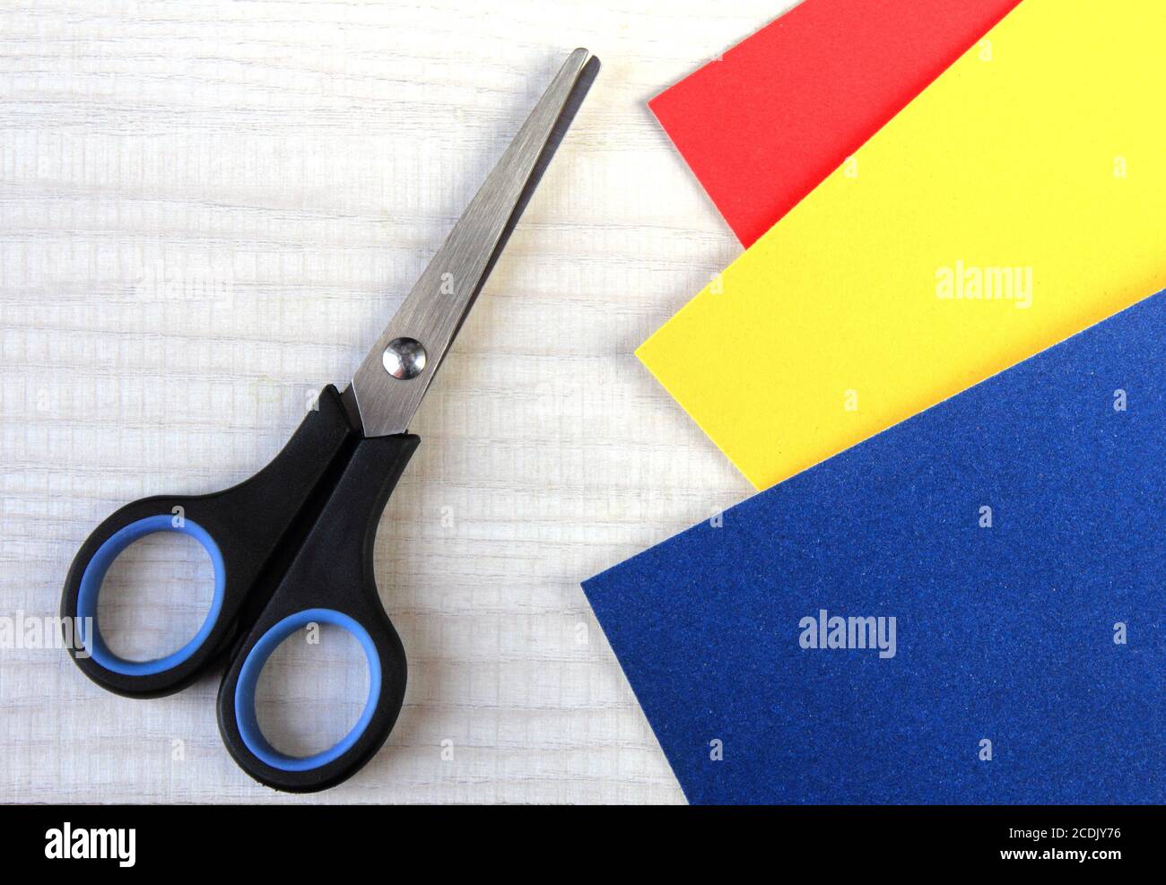 Sheets of colored paper and scissors on light wooden background. Top ...