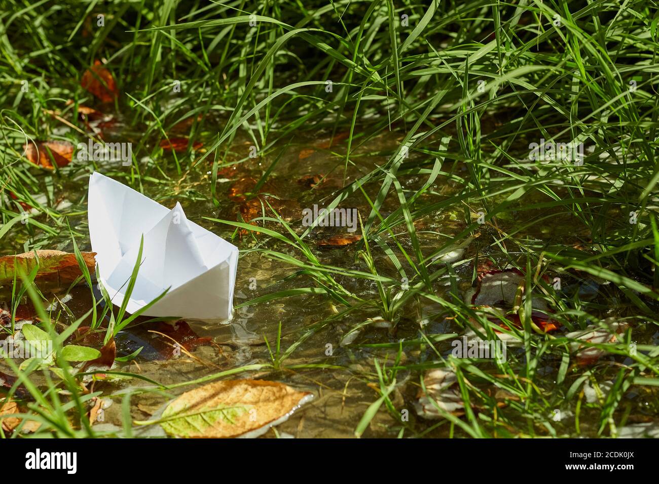 Origami boat sailing on the water. Spring waters taking away all ...