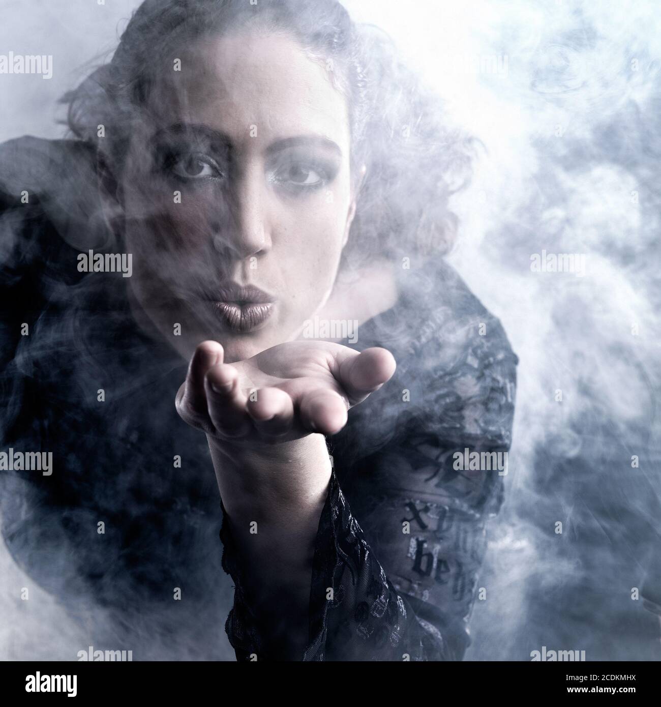 Woman with long curly hair blowing smoke Stock Photo - Alamy