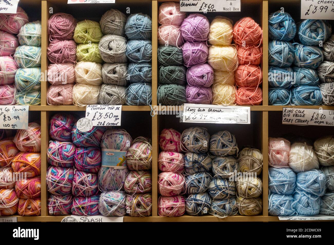 Balls of coloured knitting wool arranged on shelve on sale in a shop ...
