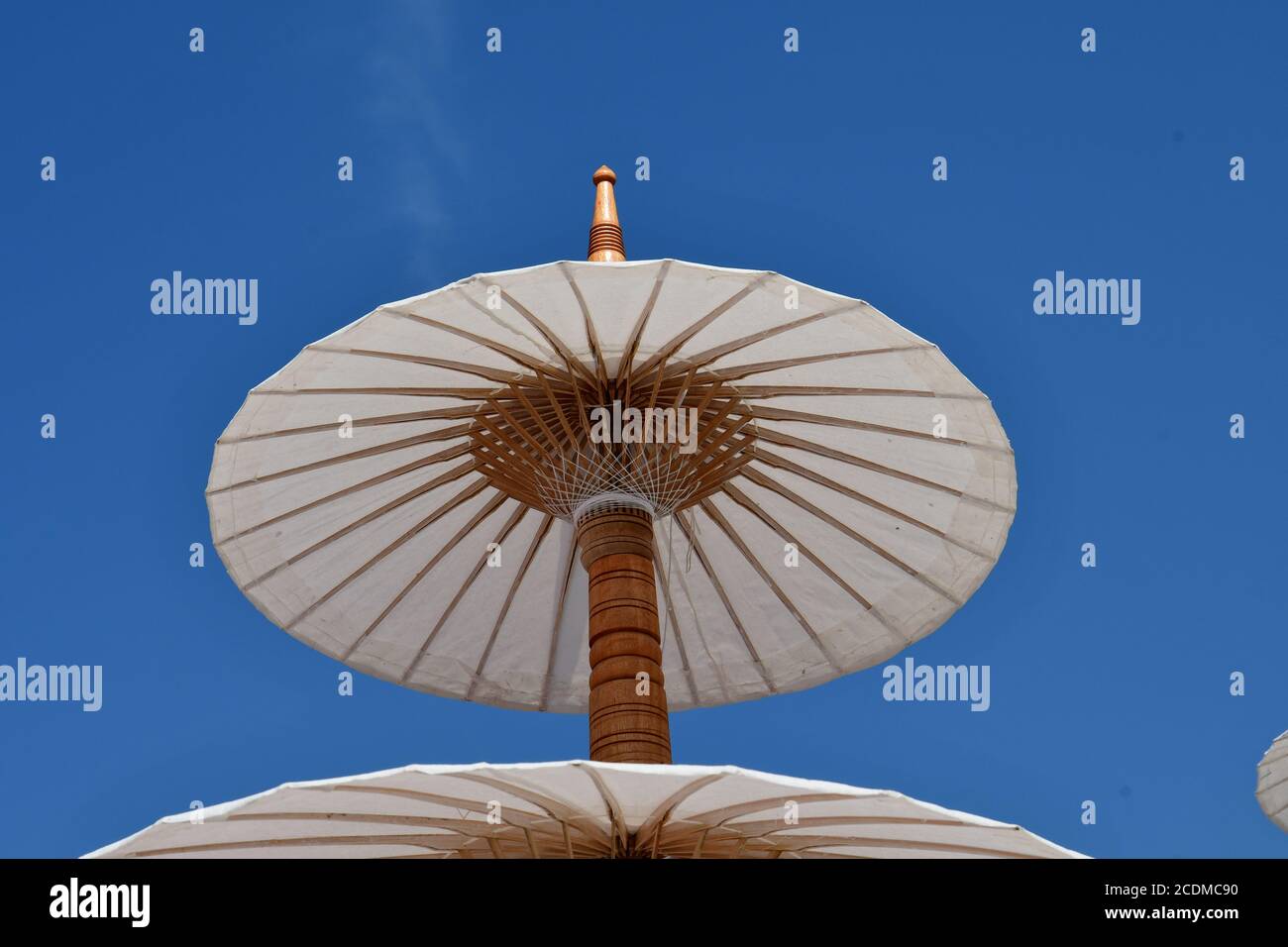 Upward persepctive view of a white paper parasol against a bright blue ...