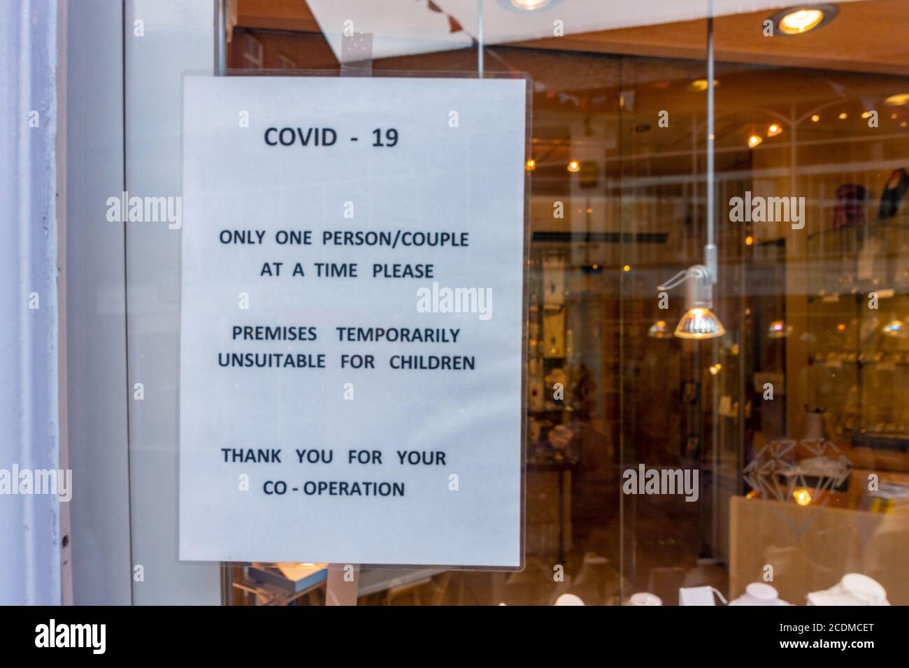 A laminated notice in a shop window tells people of restrictions to ...