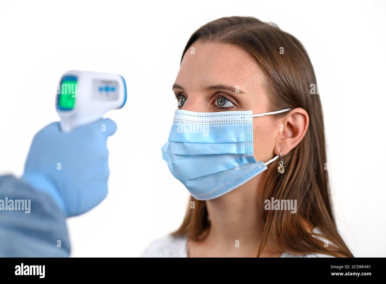 Temperature measurement with forehead thermometer, woman with face mask ...