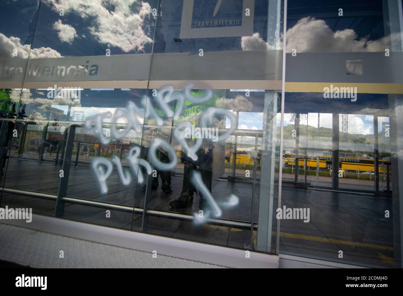 A police officer with a riot shield stands beside a graffiti with the ...