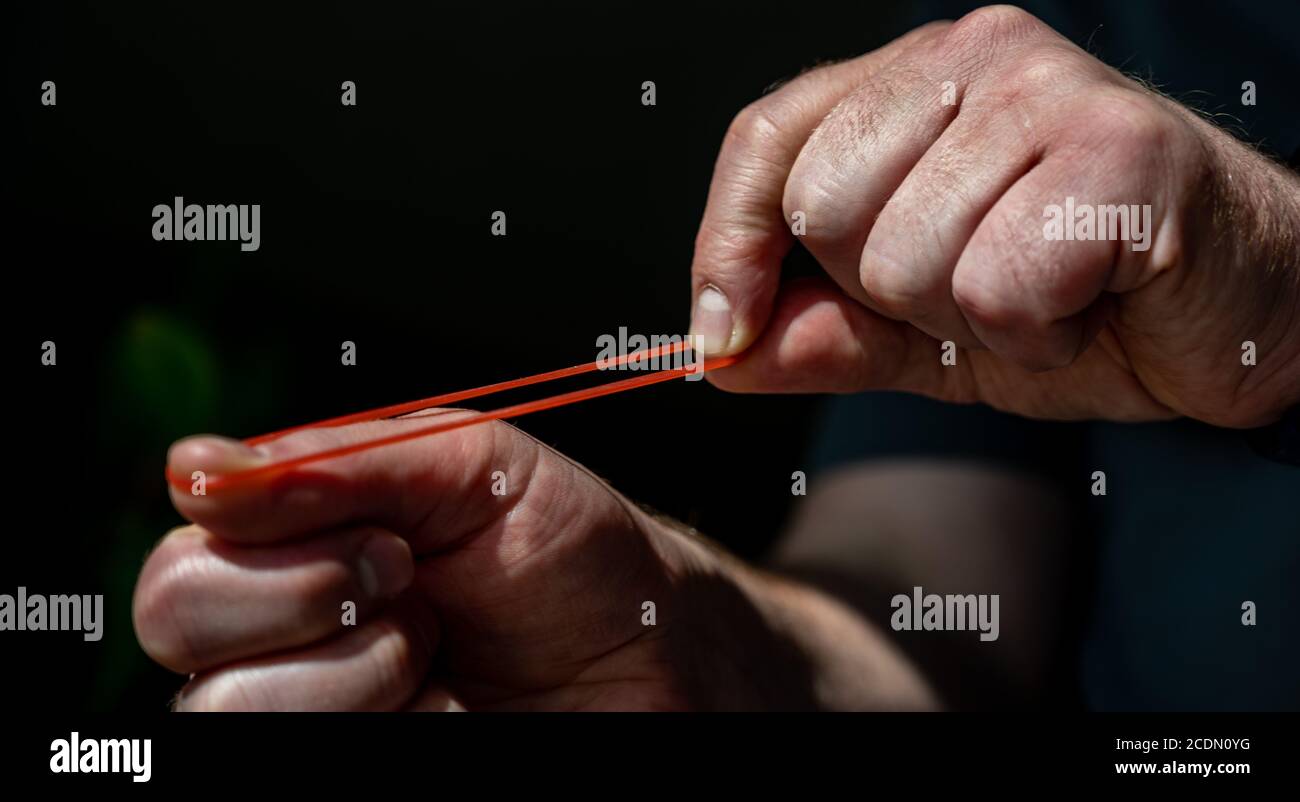 Shooting a rubber band by pulling an elastic material and letting go ...