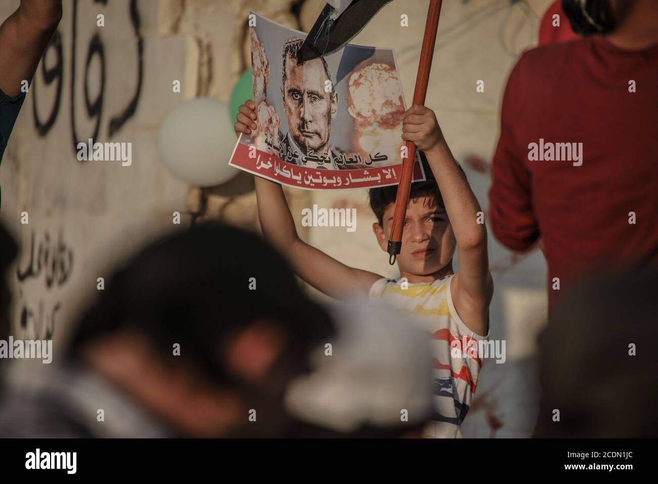 Ariha, Syria. 28th Aug, 2020. A Syrians boys holds a placard during ...